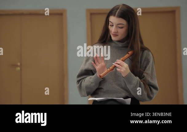 Beautiful young woman practicing on her wooden recorder flute. Talented ...