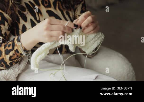 Close-up of female hands knitting with white wool yarn and needles ...
