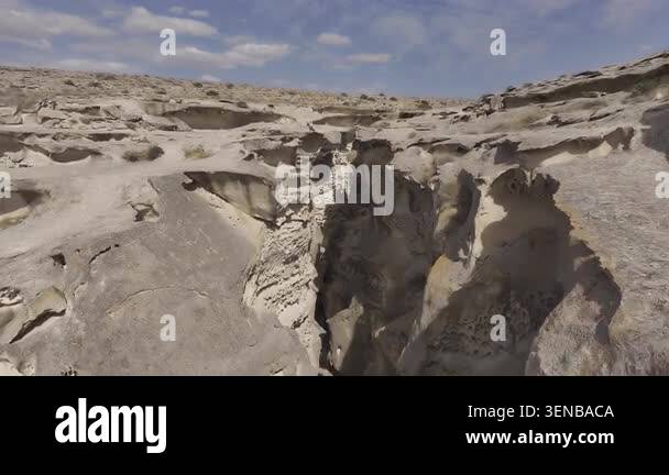 Aerial view moving through a narrow canyon in a dry, desert landscape ...