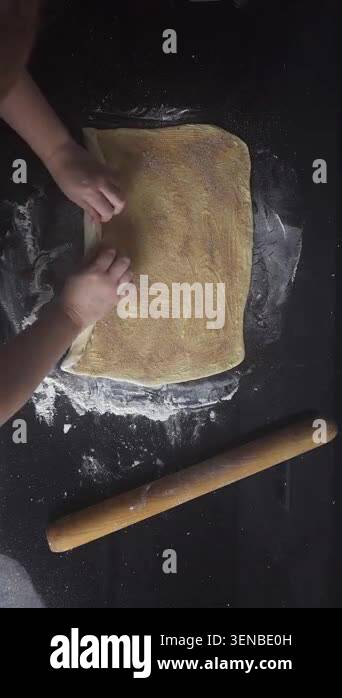 Top view of female hands rolling buttered dough covered with cinnamon ...