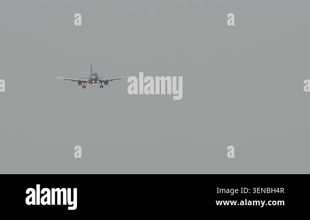 Commercial jet flying on final landing approach against grey overcast ...