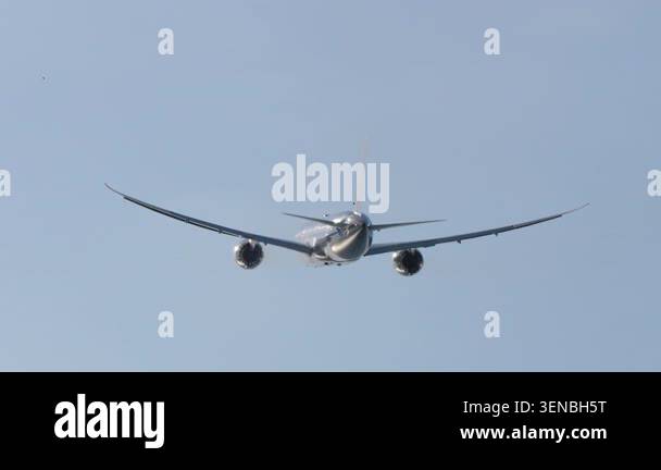 Commercial passenger airplane flying away and ascending into clear blue ...