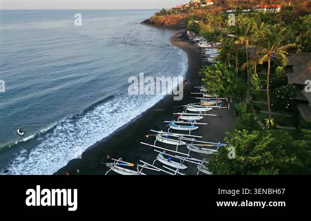 Aerial view of a black tropical beach in Bali with a wavy ocean ...