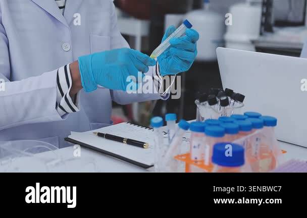 laboratory assistant holding a glass tube with chemical liquid in his ...