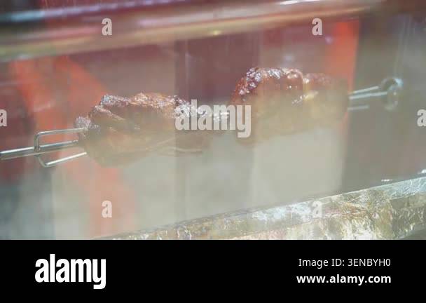 Delicious pork meat roasting on a spinning rotisserie skewer inside a ...