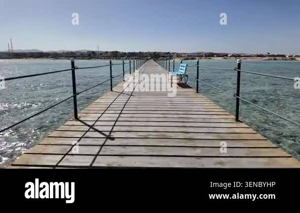 Point of view walking backward along a long wooden pier over the ...