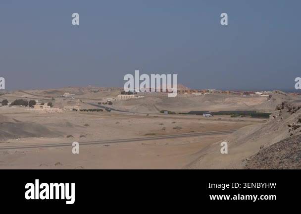 Distant view of a white tourist bus driving on an empty asphalt road ...