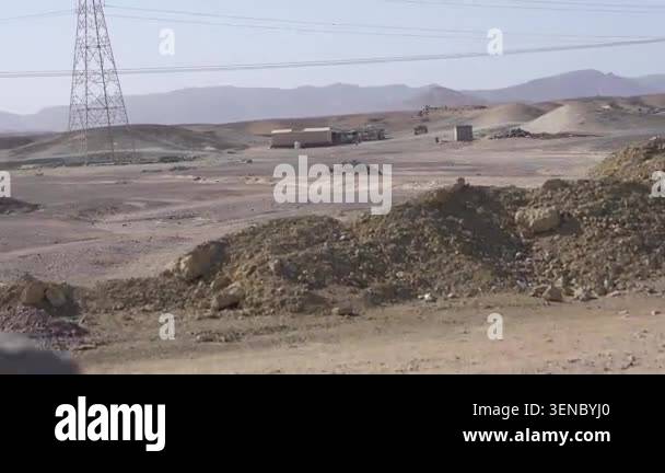 High-voltage electricity pylons standing in a vast, arid desert ...