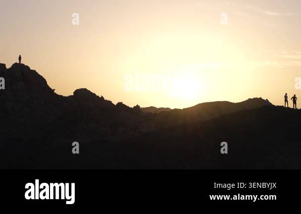 Majestic golden sun setting behind the dark silhouettes of mountains in ...