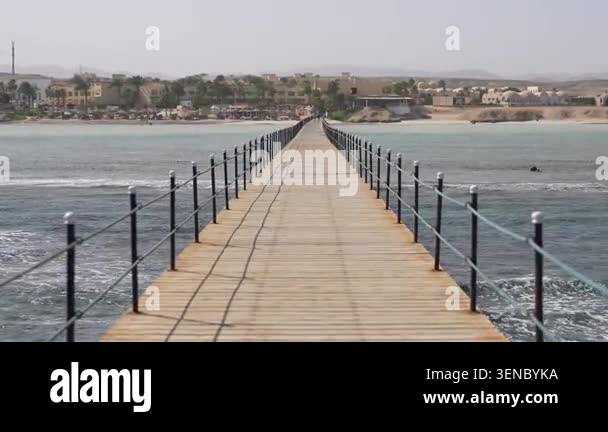 Young woman walking away from the camera on a long wooden jetty over ...
