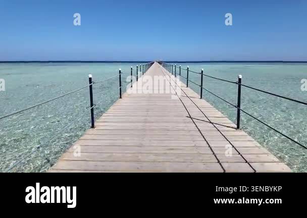 First person perspective walking along a long wooden pier extending ...