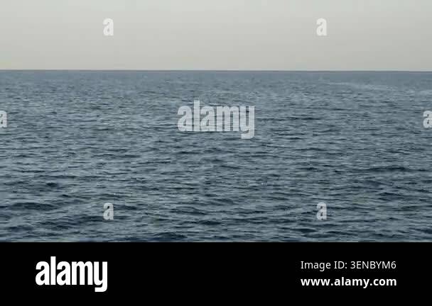 Vast deep blue ocean water gently moving under a calm, overcast sky ...
