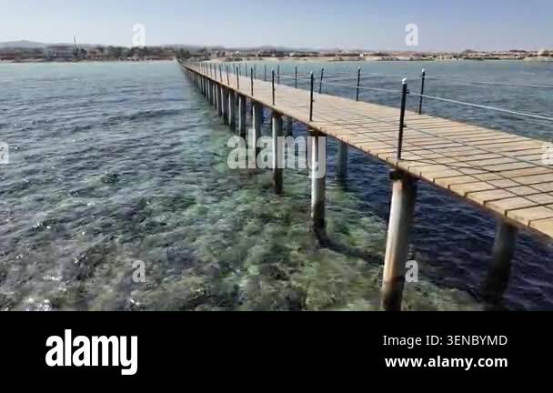 Empty wooden pier standing on stilts over the crystal clear turquoise ...