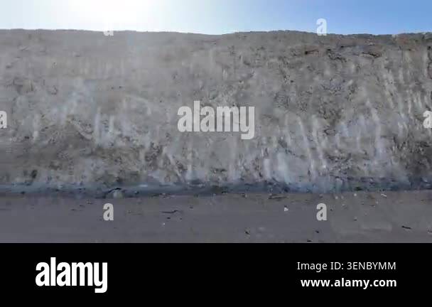 Off-road vehicle driving from an asphalt road onto a dusty trail for a ...