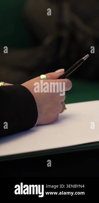 Close-up of a nervous businesswoman's hand fidgeting with a pen above a ...