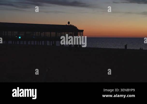 Silhouettes of people enjoying the evening on a pebble beach in batumi ...