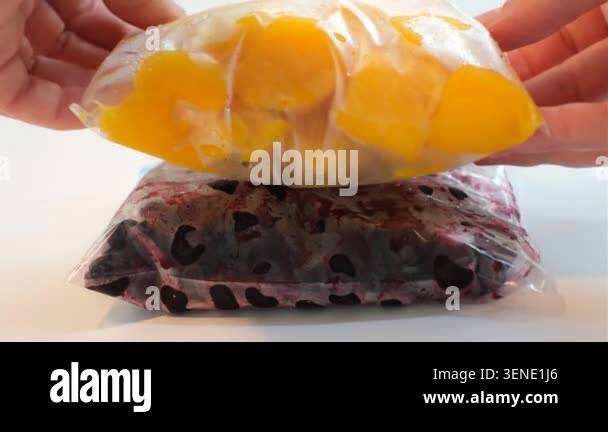 Female hands stack packages of frozen fruits on top of each other on ...