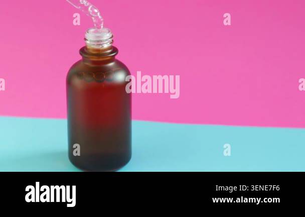 Bottle with serum and pipette on pink and blue background close-up ...