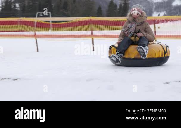 Front view of young happy girl in warm winter coat riding on yellow ...