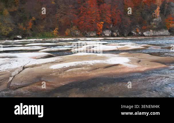 Shallow mountain river rapids with evergreen autumn terracotta forests ...