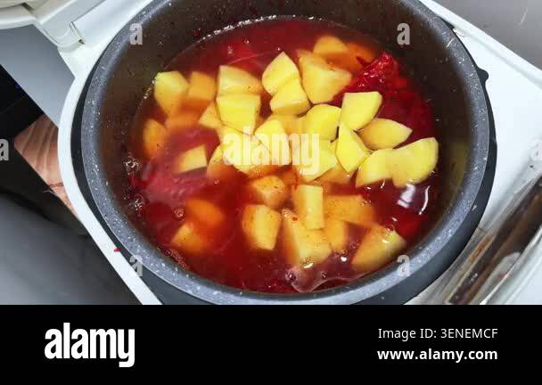 Pouring water to meat, vegetables in multicooker for borscht cooking ...