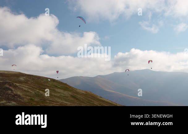Paragliding active sports with parachute flying against mountains with ...