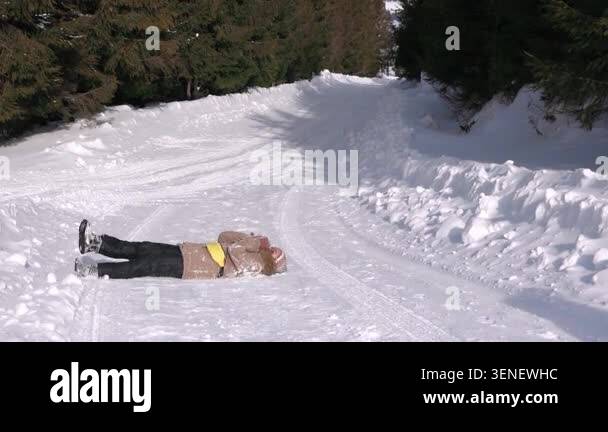 Side view of female kid in warm coat and mittens rolling down hill ...