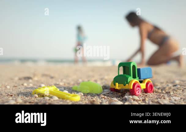 Many bright multi-colored plastic toys lie on a large sea sandy beach ...