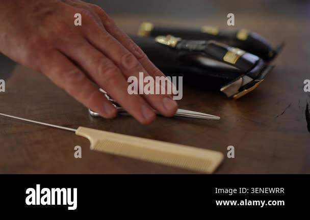 Male hairstylists hand taking professional scissors from a wooden table ...