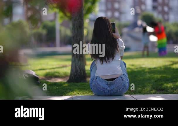 Rear view of a young relaxed woman with long dark hair sitting on the ...