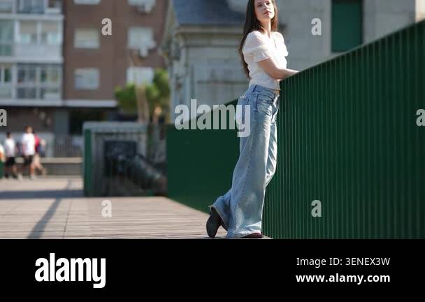 Portrait of a contemplative young woman with long hair standing on a ...