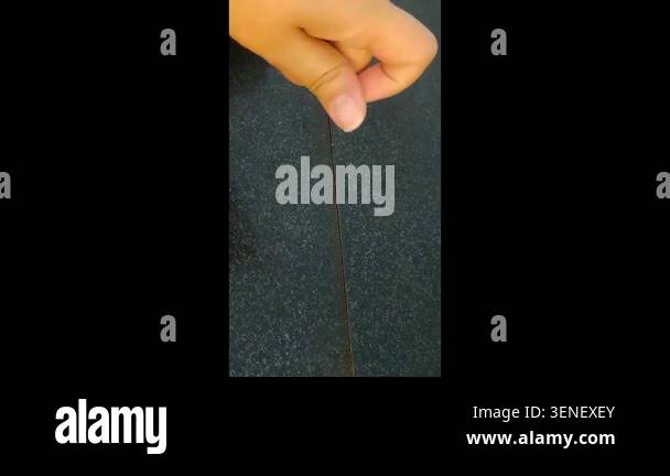 A vertical close-up shot of a hand touching the surface of a dark ...