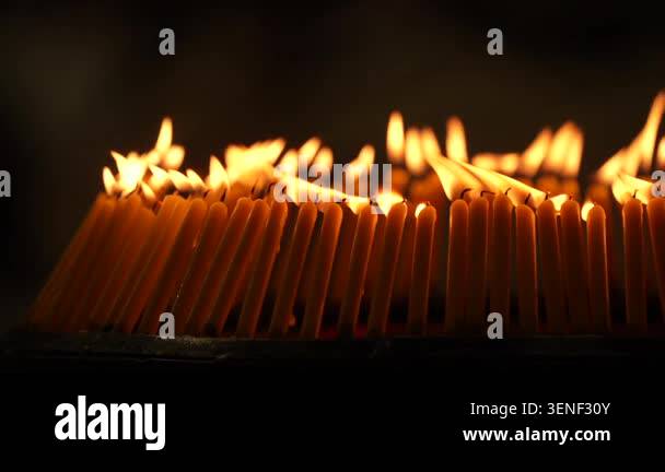 Rows of warm candle flames in a dark temple setting create a sacred ...