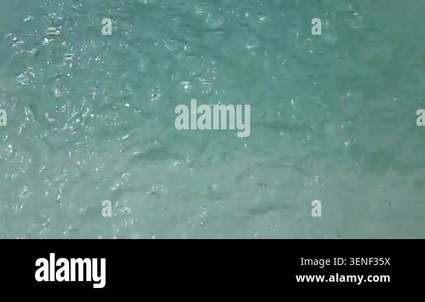 A wide shot of clear turquoise water surface in a swimming pool during ...