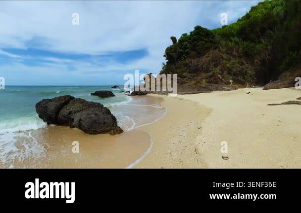 Turquoise waves crashing over the sandy beach and rocks. Santa Fe ...