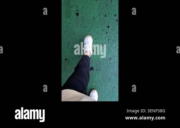 A first-person perspective of someone walking on a bright green ...