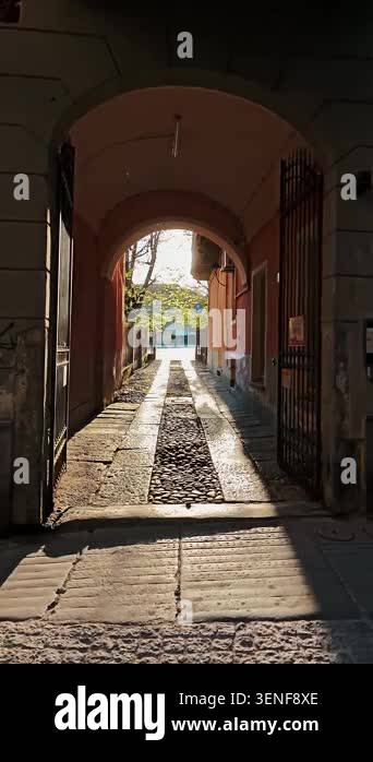 Shadowy vaulted archway opening toward sunlit cobblestone square. Old ...