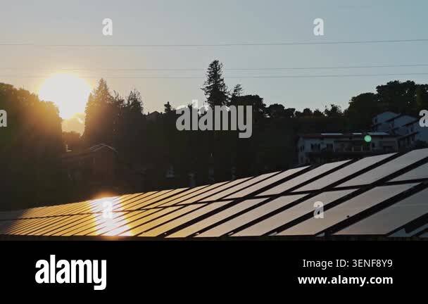 Rooftop solar energy system glowing in warm sunset light with trees ...