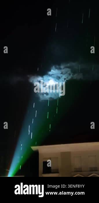 Magical scene of light beam revealing falling raindrops with glowing ...
