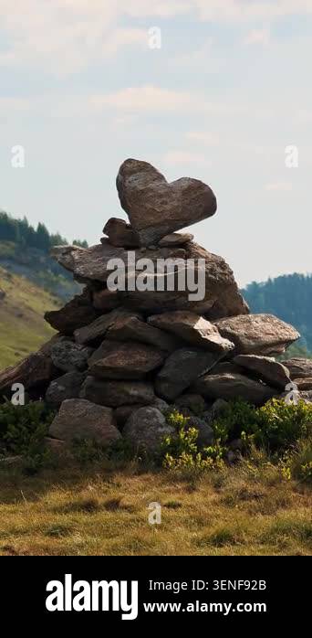 Traditional stone cairn trail marker standing on alpine meadow under ...