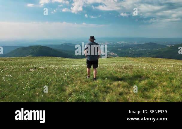 Young male hiker walking through alpine narcissus meadow with small ...