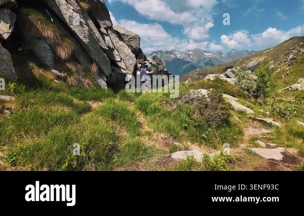 Distant lone hiker walking along scenic rocky alpine trail through ...