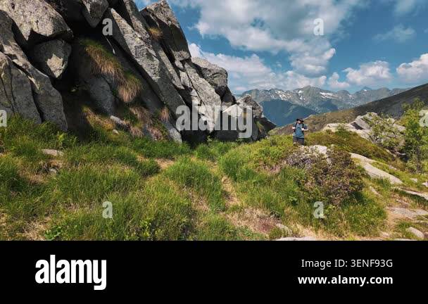 Hiker walking along rocky alpine trail with dramatic rock formations ...