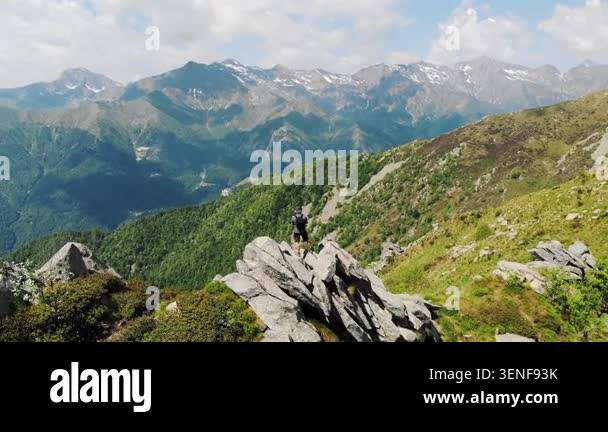 Man standing on large boulders at mountain peak with sweeping wide ...