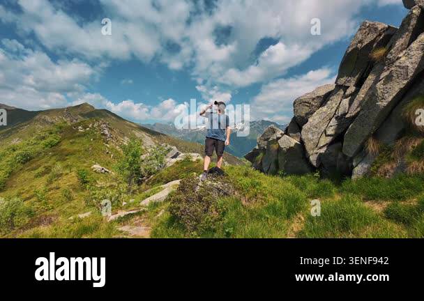 Lone traveler drinking water from bottle while taking break on rocky ...