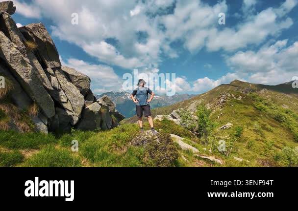 Hiker standing on rocky alpine trail resting and contemplating scenic ...