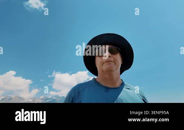 Happy male hiker in sun hat blowing air kiss toward camera with bright ...