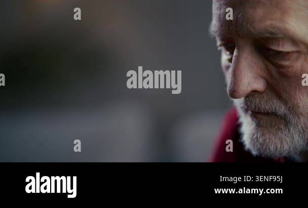 Close-up profile of an elderly man looking downward with a thoughtful ...