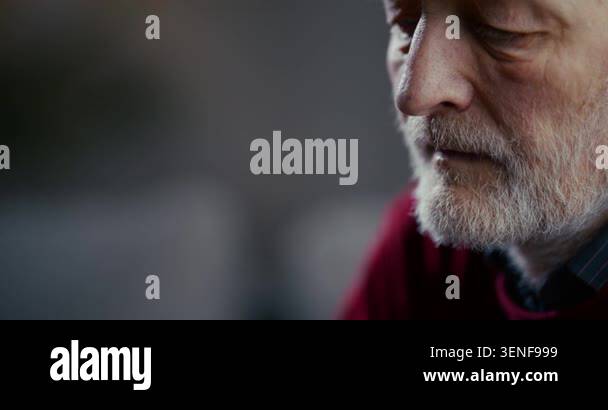 Close-up profile of an elderly bearded man looking downward with a calm ...