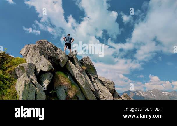 Hiker standing on top of large rocky boulder contemplating scenic ...